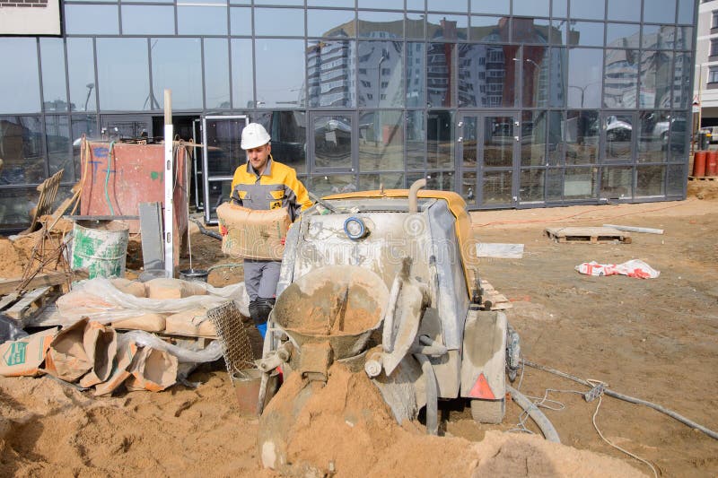 A Builder in Work Clothes is Doing His Job, Leveling the Floor, Pouring ...