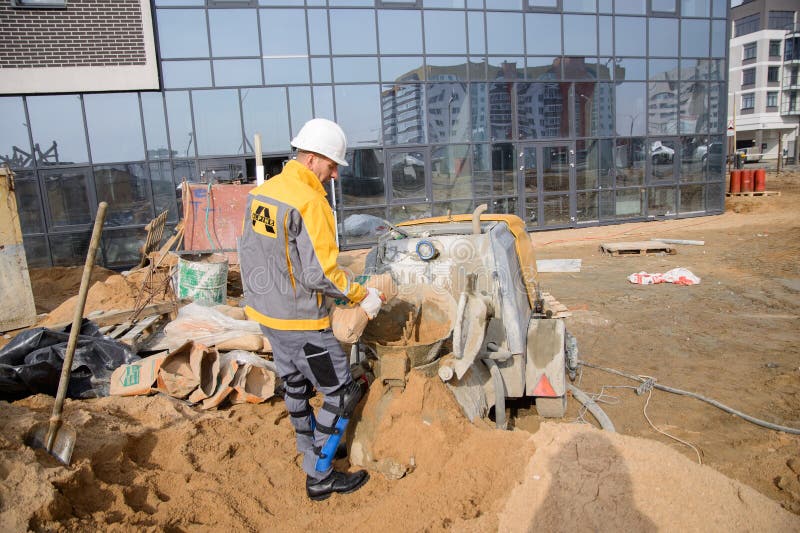 A Builder in Work Clothes is Doing His Job, Leveling the Floor, Pouring ...