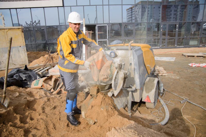 A Builder in Work Clothes is Doing His Job, Leveling the Floor, Pouring ...