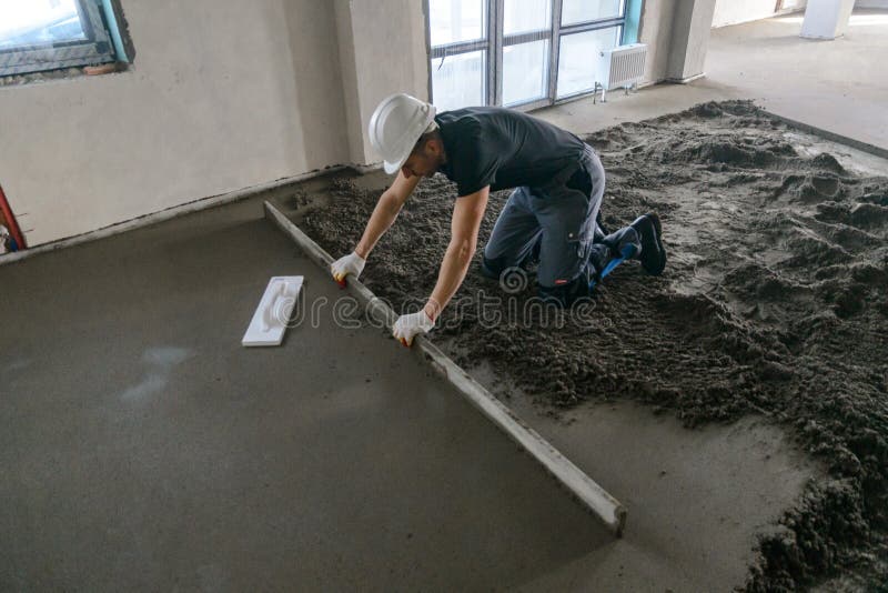 A Builder in Work Clothes is Doing His Job, Leveling the Floor, Pouring ...