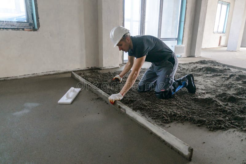 A Builder in Work Clothes is Doing His Job, Leveling the Floor, Pouring ...