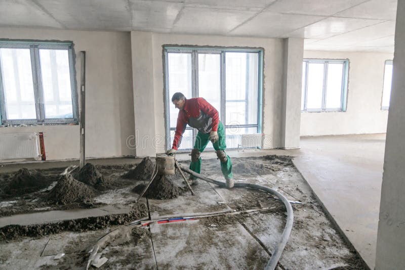 A Builder in Work Clothes is Doing His Job, Leveling the Floor, Pouring ...