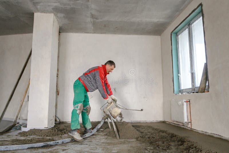 A Builder in Work Clothes is Doing His Job, Leveling the Floor, Pouring ...