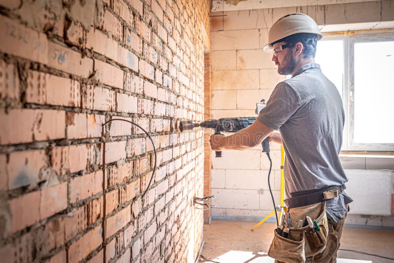 A Builder Works with a Drill at a Construction Site Stock Photo - Image ...