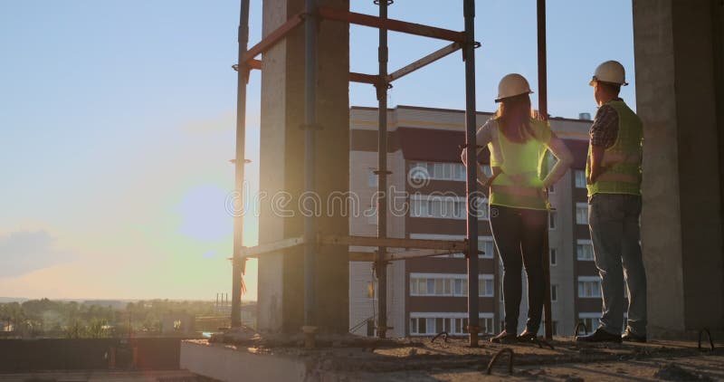 Builders Look at a Cityscape on a Sunset Background, Back View Stock ...