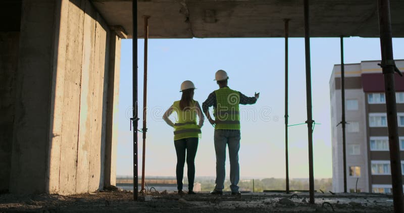 Builders Look at a Cityscape on a Sunset Background, Back View Stock ...
