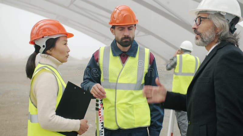 Builders Talking at Construction Site while Architect Coming Discussing ...
