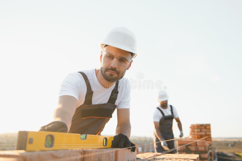 Builders Work at the Construction Site in Overalls and Helmets ...