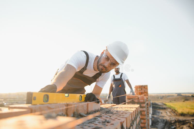 Builders Work at the Construction Site in Overalls and Helmets ...