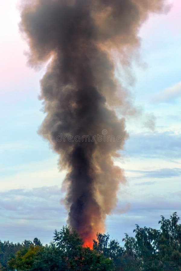 The Building Burns with Fire and Black Smoke Against the Evening Sky ...
