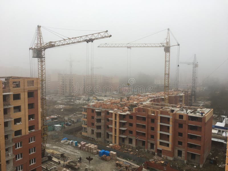 Building cranes in the fog stock image. Image of construction - 140189623