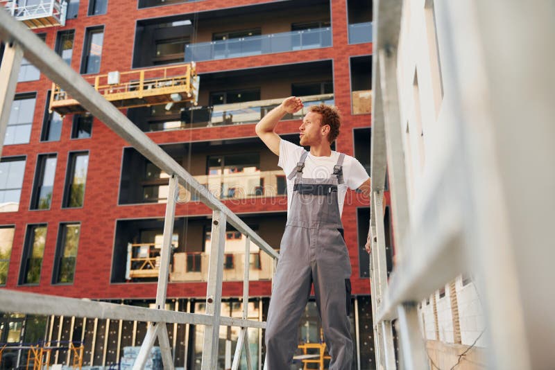 Building Exterior. Young Man Working in Uniform at Construction at ...