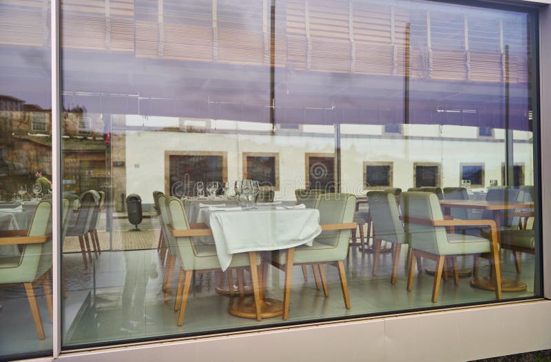 Building Facade Reflects Restaurants Tables and Chairs through Large ...