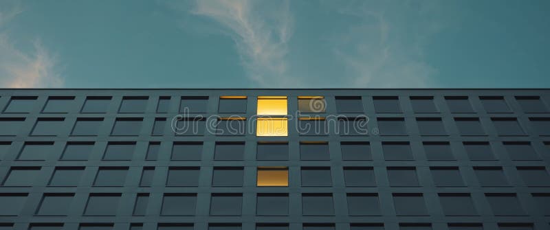 A Building with Many Windows and a Yellow Light Shining through One of ...