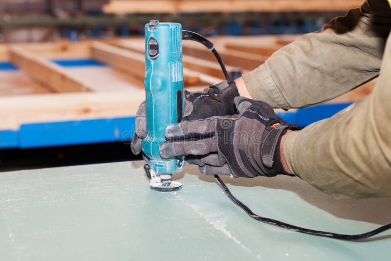 Building a Wall for Frame House. Worker Use Laminate Trimmer for ...