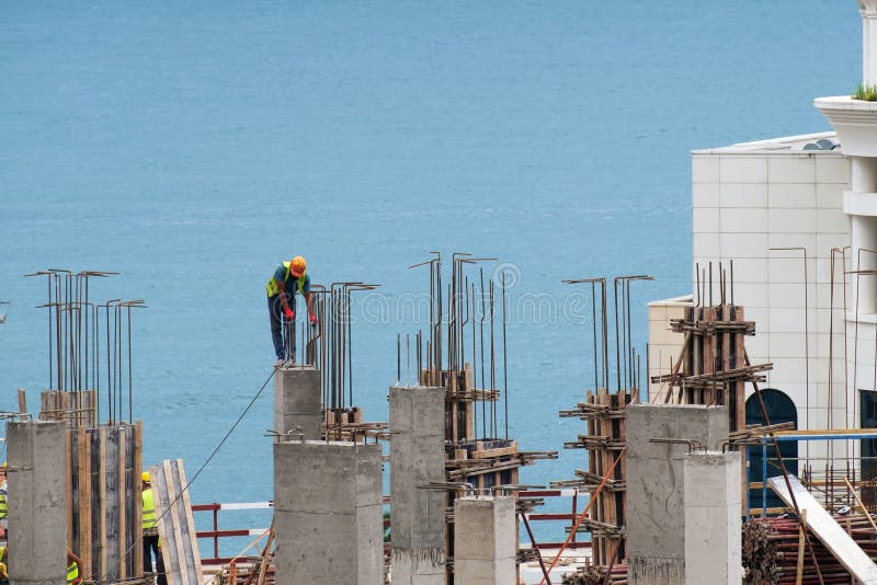 Worker Working on the Top of the Construction Site with Blue Sea ...