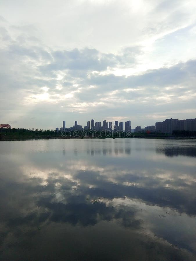 Buildings and Clouds Reflected in Calm Lake. Reflection Mirror in City ...