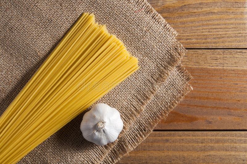 Bulb of Garlic and Spaghetti on Burlap on Brown Wooden Table. Top View ...