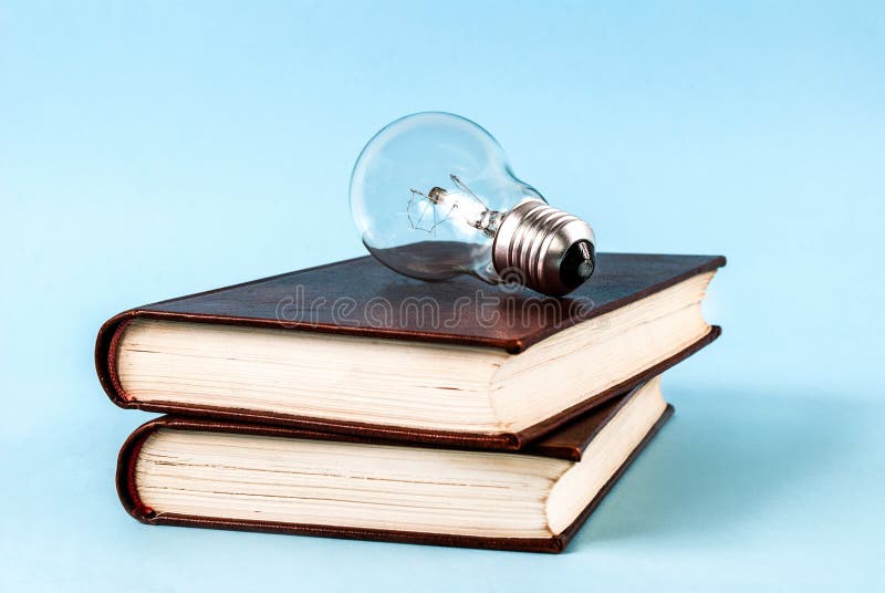 Bulb on Two Closed Books Isolated on a Blue Background Stock Photo ...