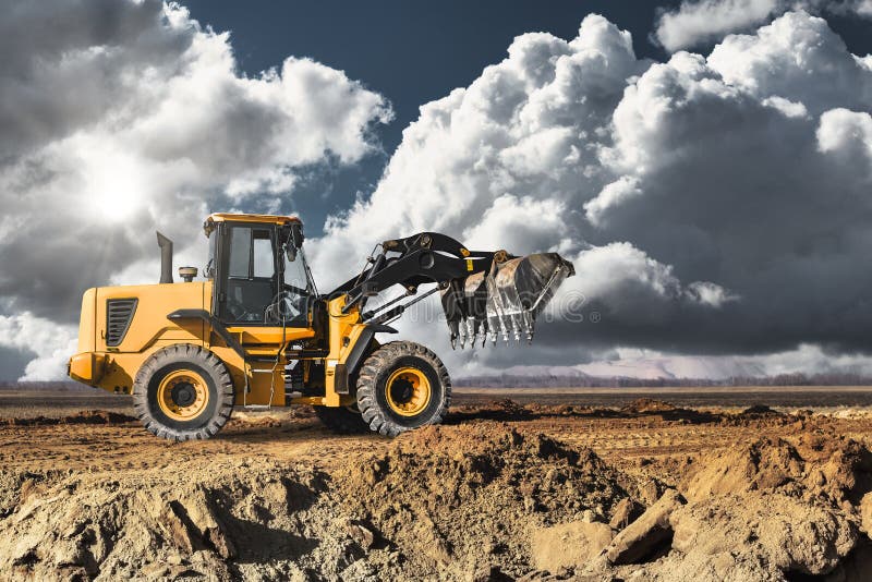 Bulldozer or Loader at a Construction Site Shovels Mountain Soil into a ...