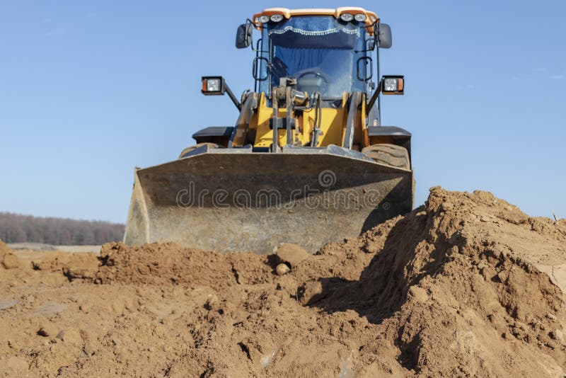 Bulldozer or Loader Moves the Earth at the Construction Site Against ...