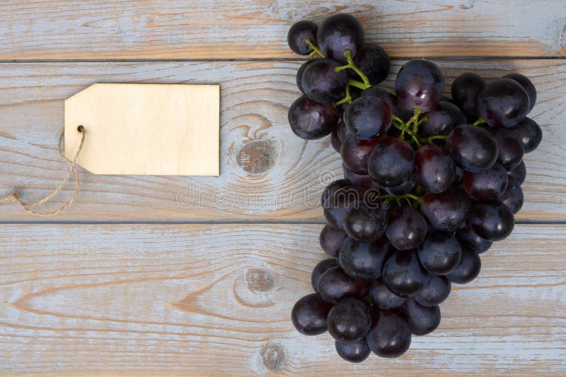 Bunch of Fresh Organic Black Grapes and a Blank Label Tag on a Wooden ...