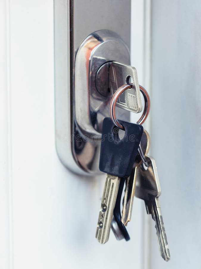 Bunch of Keys Inserted in Door Lock on White Door Stock Image - Image ...