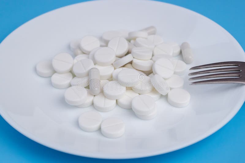 A Bunch of Medcin Tablets with a Fork on a Plate on a Blue Background ...