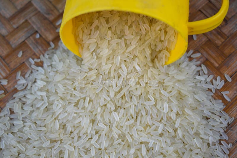 Bunch of Rice Grain Falling from a Yellow Cup on a Wooden Colored ...