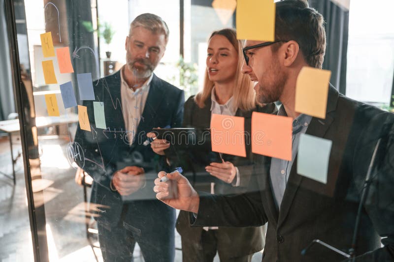 Bunch of the Stickers are on the Glass. Group of Business People are ...