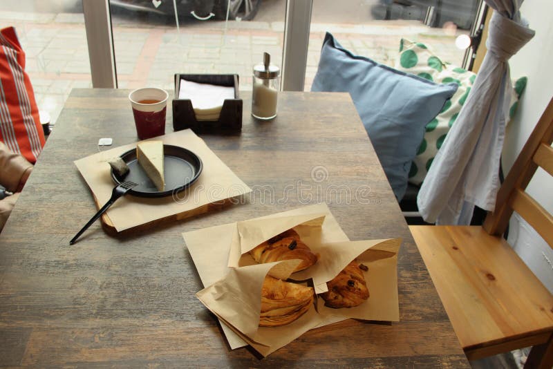 Buns in Paper Bags and a Piece of Cake are on the Table in a Cafe ...