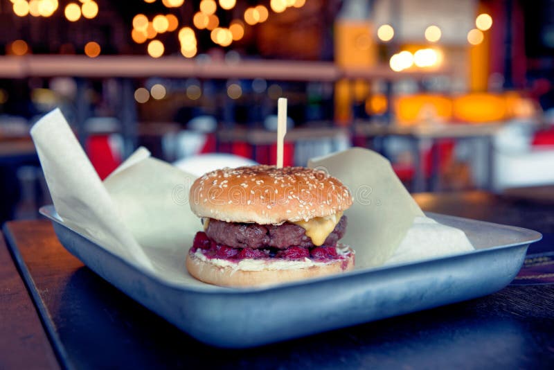 Burger with Sour Marinated Cherry on Restaurant Table, Toned Stock ...