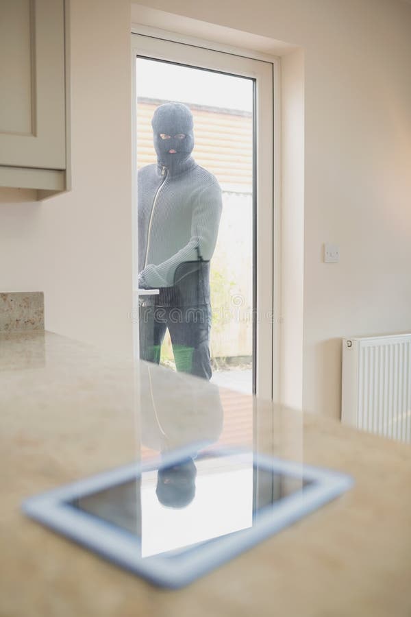 Burglar Looking at Tablet Pc through Kitchen Door Stock Photo - Image ...
