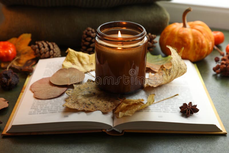 Burning Candle, Autumn Decor and Open Book on Green Background Stock ...