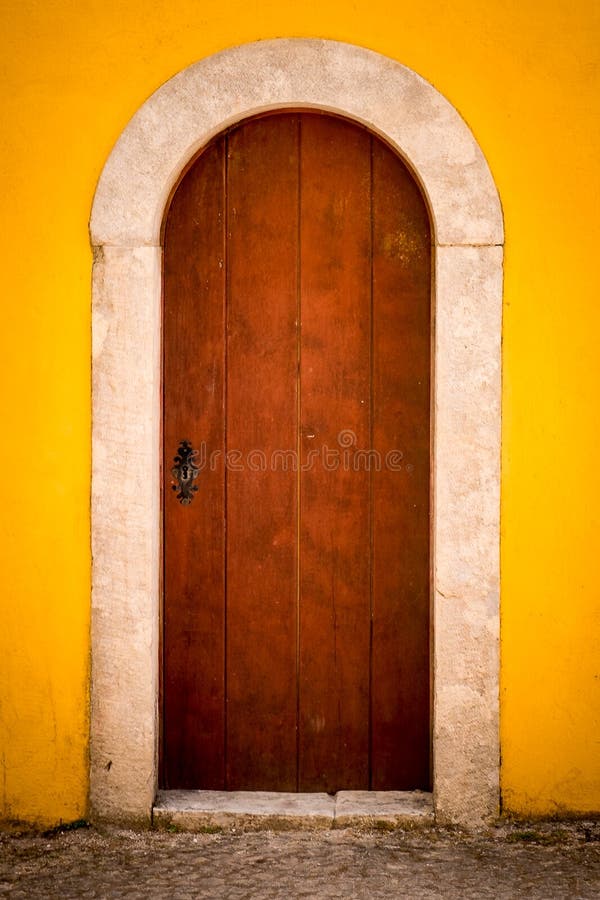 Burnt Orange Arch Shaped Door Against a Yellow Wall Stock Photo - Image ...
