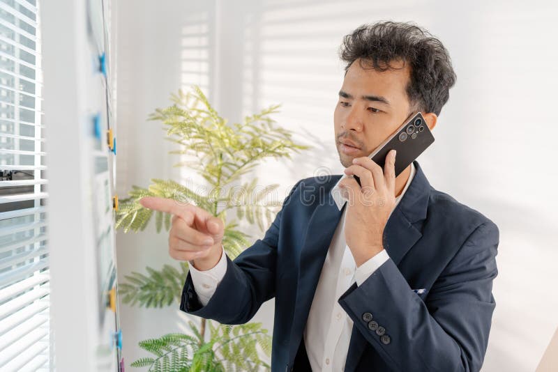 A Business Analyst Examining Charts and Statistics on a Whiteboard, Using Data-driven Insights ...