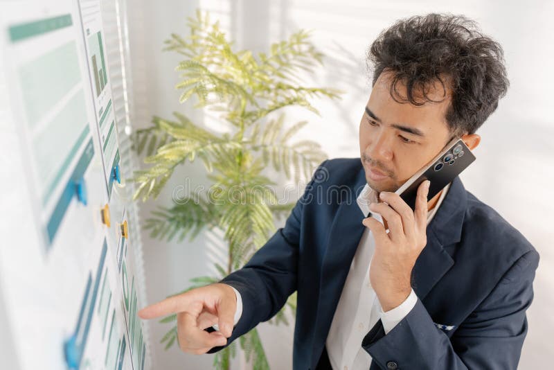 A Business Analyst Examining Charts and Statistics on a Whiteboard, Using Data-driven Insights ...