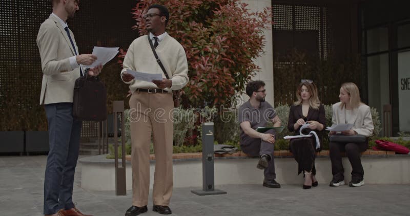Business Professionals Collaborate: a Team Meeting Outdoors Reviewing ...