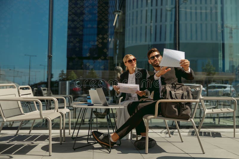 Business Colleagues Working with Documents Sitting Outside of Office on ...