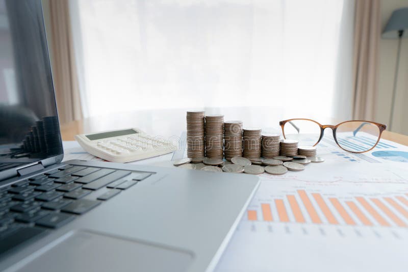 Business Documents on Table with Laptop and Coin Stacks and Graph ...