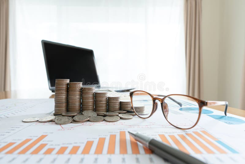 Business Documents on Table with Laptop and Coin Stacks and Graph ...