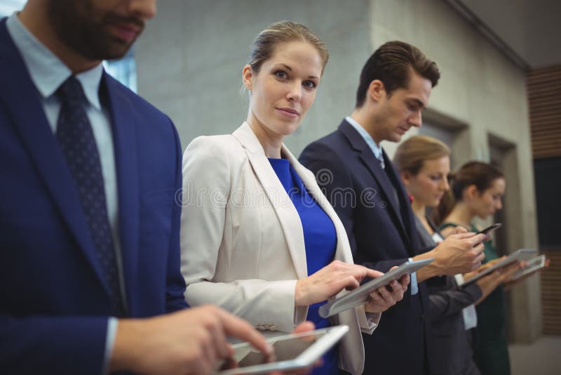 Business Executives Using Electronic Devices in Corridor Stock Photo ...
