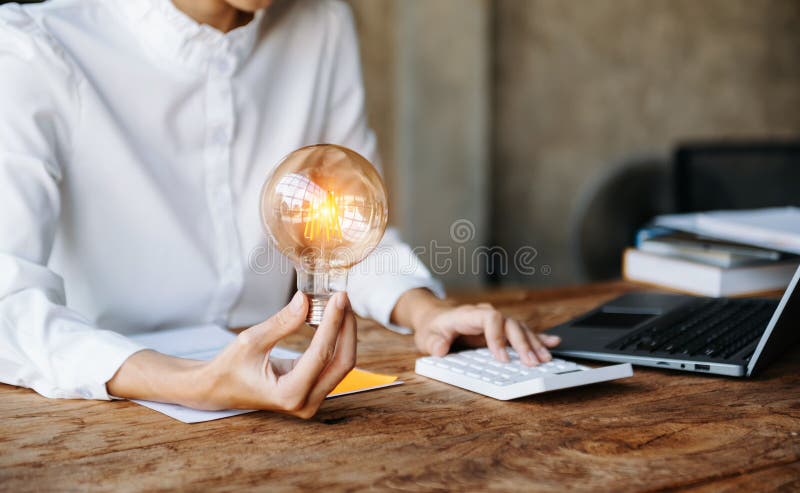 Business Hand Holding Lightbulb with Using Laptop Computer and Money ...