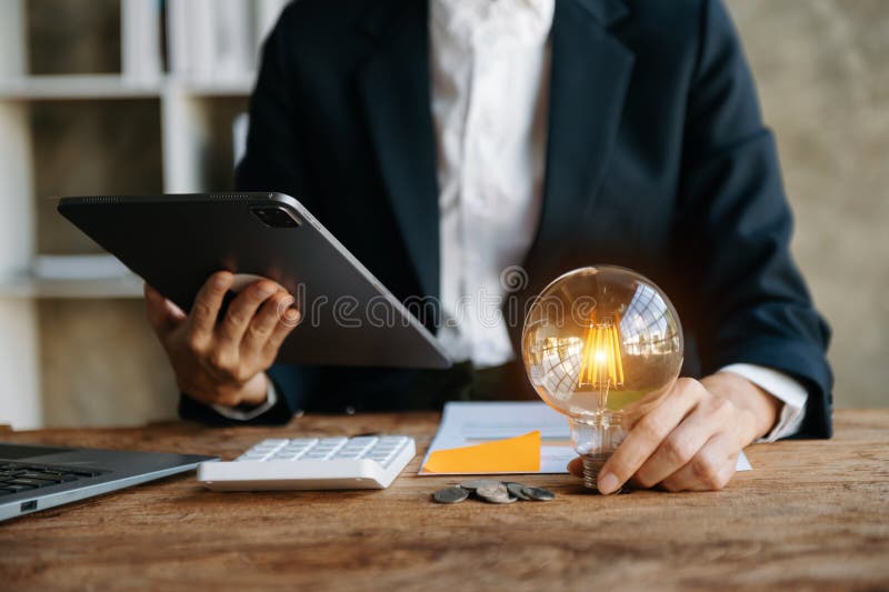 Business Hand Holding Lightbulb with Using Laptop Computer and Money ...