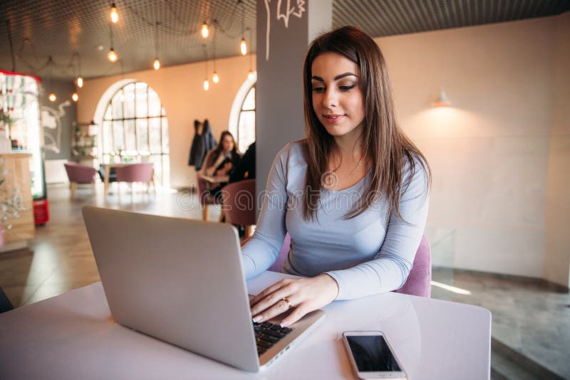 Business Lady Sitting in Cafe and Working on a Laptop and Using Phone ...