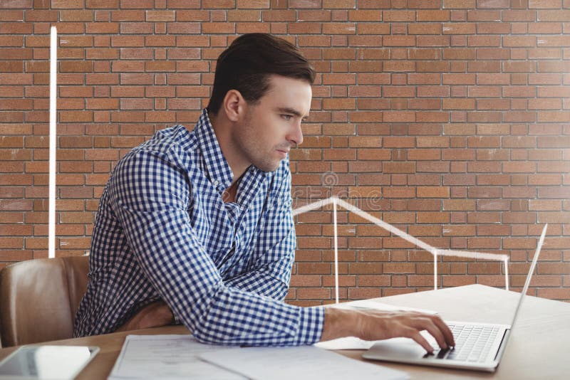 Business Man at a Desk Using a Computer Against Brick Wall with ...