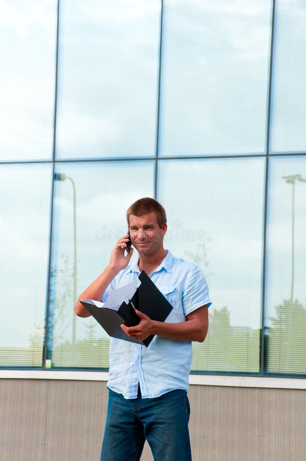Business Man with Notebook and Mobile Phone in Front of Modern Business ...