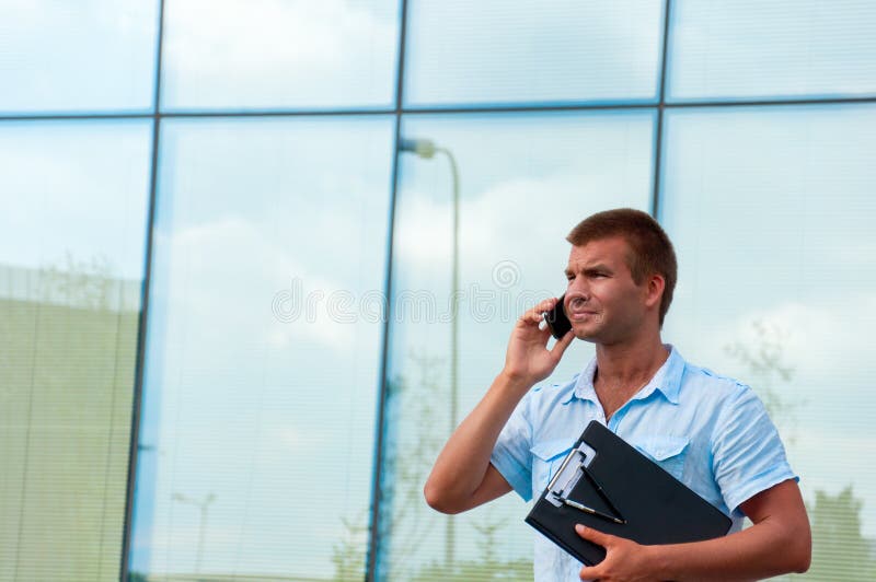 Business Man with Notebook and Mobile Phone in Front of Modern Business ...