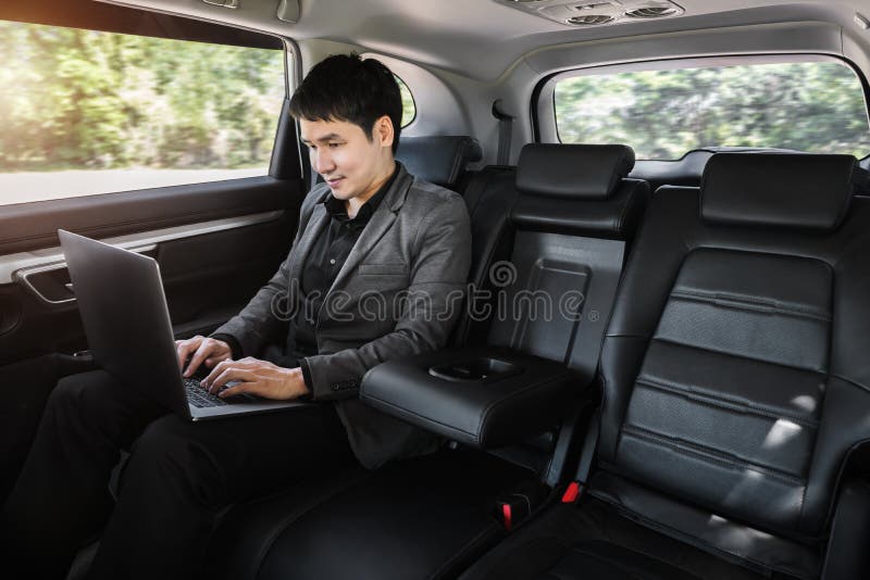 Business Man Using Laptop Computer while Sitting in the Back Seat of ...