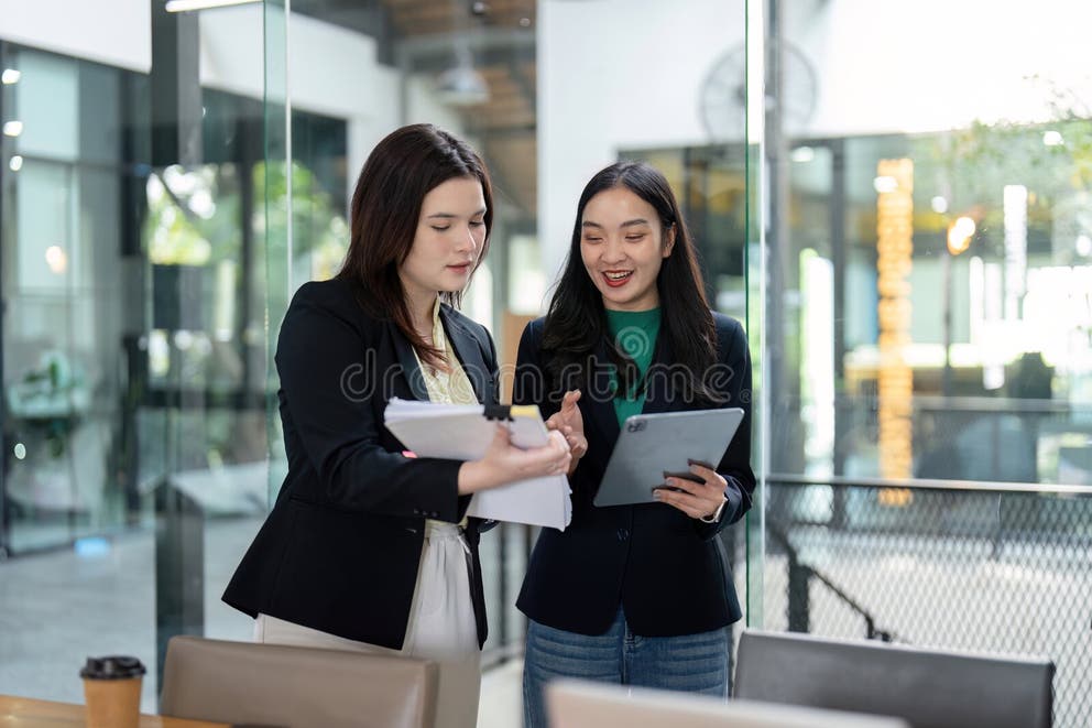 Business Partners Collaborating on a Project with Documents and a Tablet in a Modern Office ...